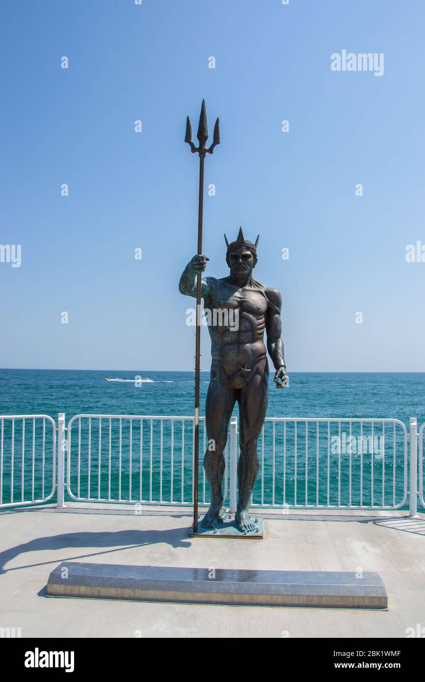 Pier with statue of Poseidon (or Neptune), close-up, blue sea and sky ...