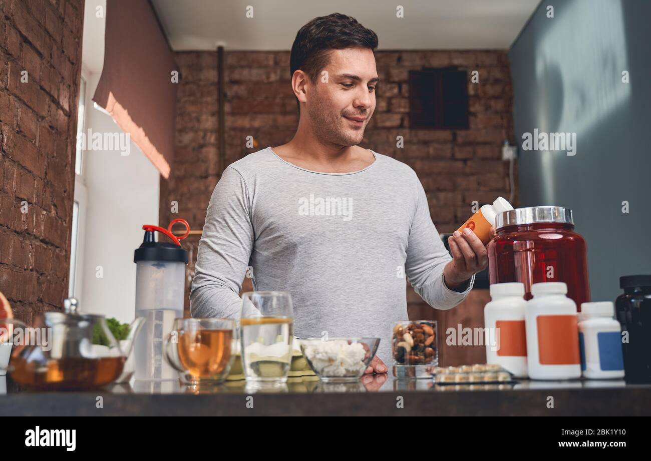 Fit man examining a dietary supplement in his hand Stock Photo - Alamy