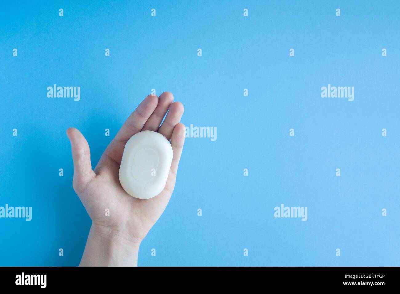 A piece of soap in a male hand a top view on a blue background. The ...