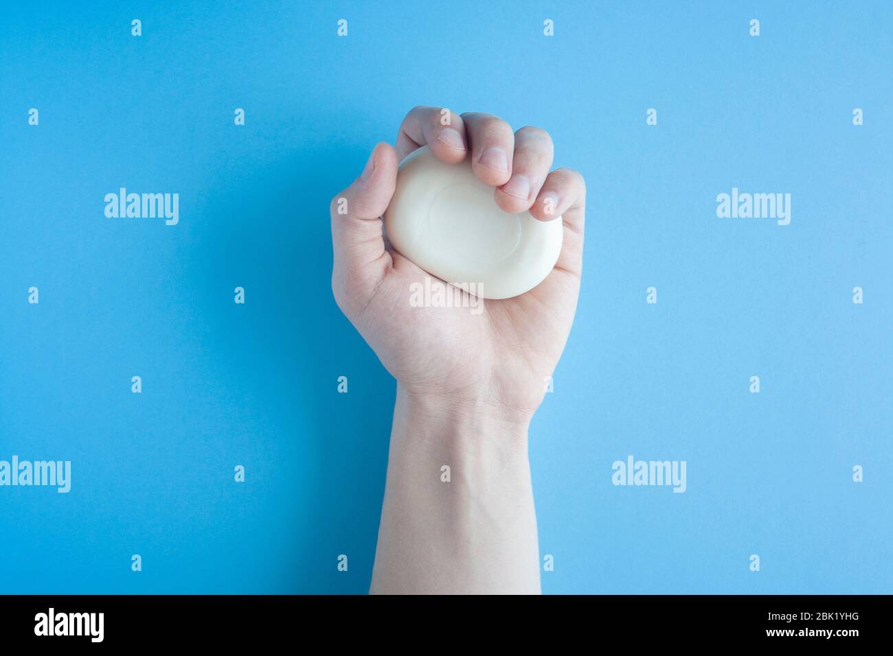 A piece of soap in a male hand a top view on a blue background. The ...