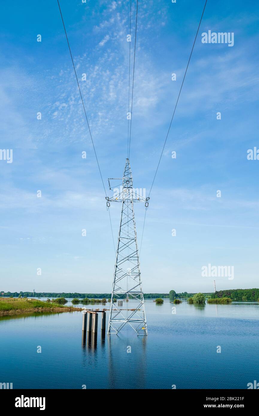 The high voltage power lines on water. Blue sky and green trees during ...