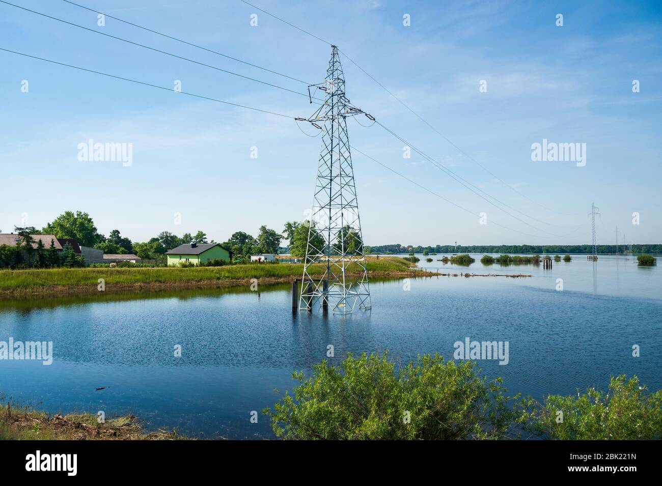 The high voltage power lines on water. Blue sky and green trees during ...