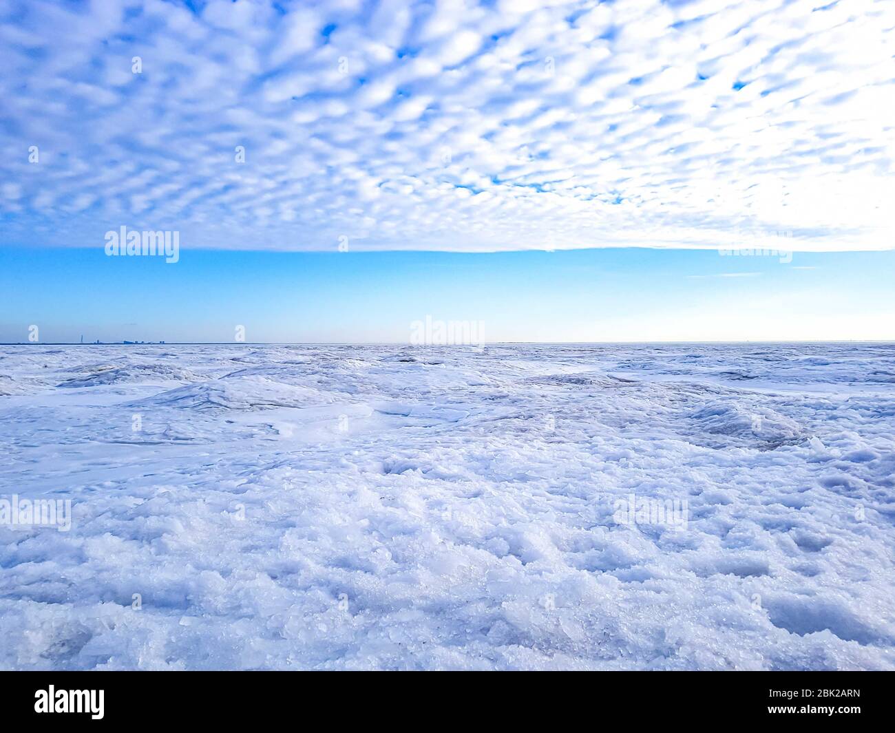 Winter costal landscape with frozen sea, blue sky and beautiful fleecy ...