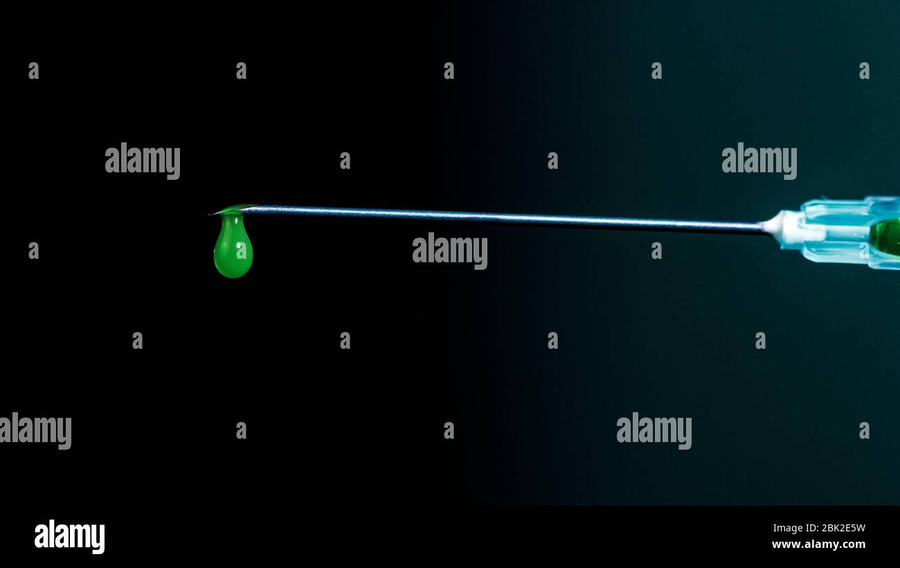 Syringe with green toxic poison liquid isolated on dark background ...