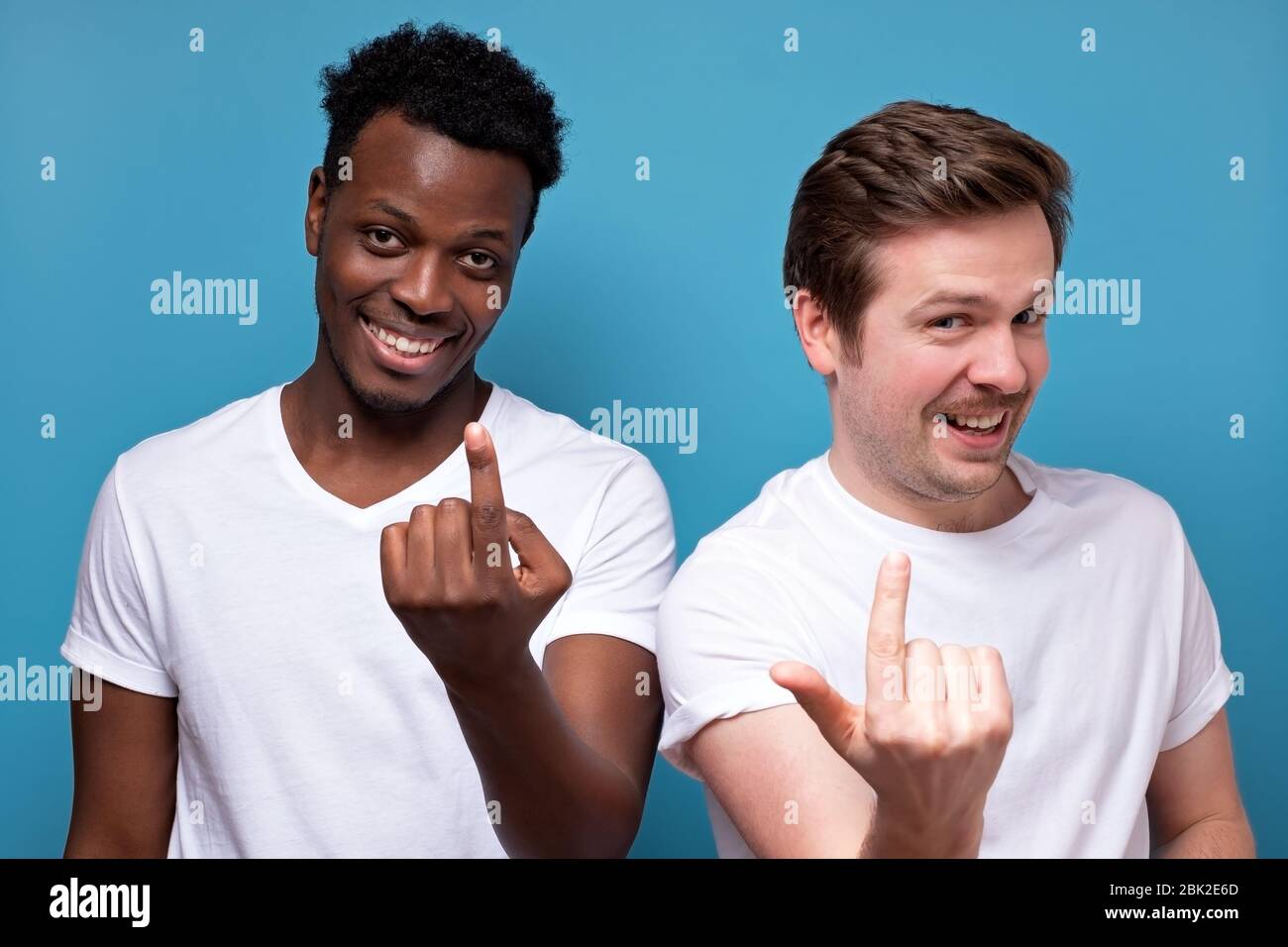 Two adult showing come here gesture with index finger and smiling over ...