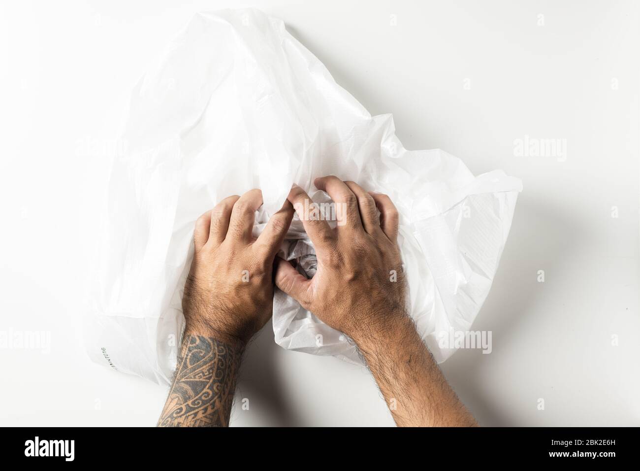 Man hand with tattoos squeezing a crumpled foam sheet isolated on white ...