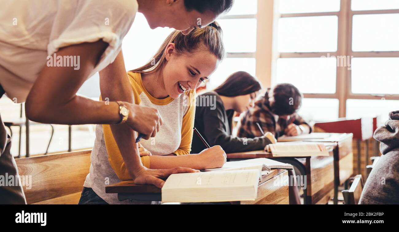 Student attending lecture with teacher helping in studies. Girl sitting ...