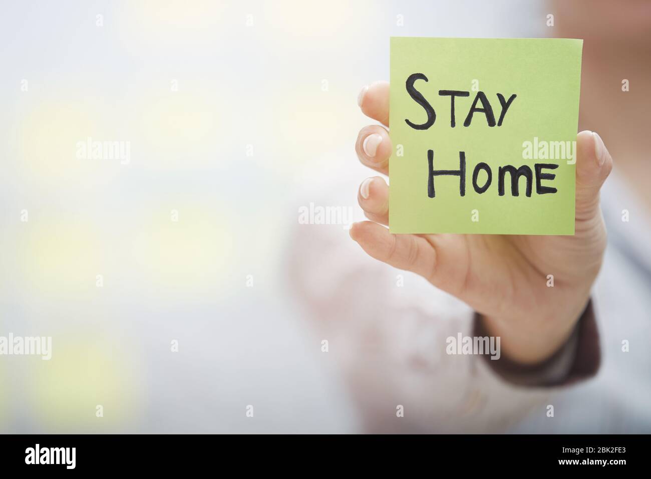 Hand holding sticky note with Stay Home text Stock Photo - Alamy