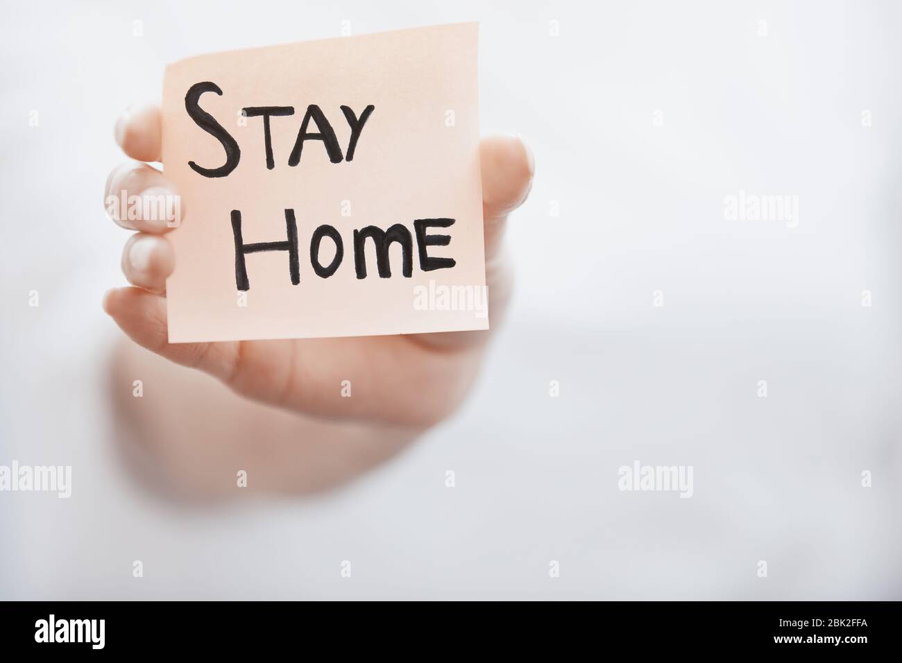 Hand holding sticky note with Stay Home text Stock Photo - Alamy