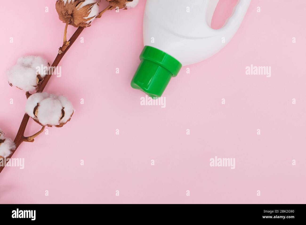 Liquid washing detergent in plastic bottle and cotton flowers on pink ...