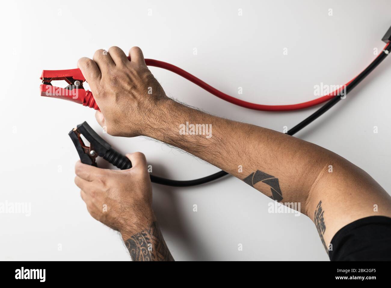 Man hand with tattoo holding jumper cable isolated on white background ...