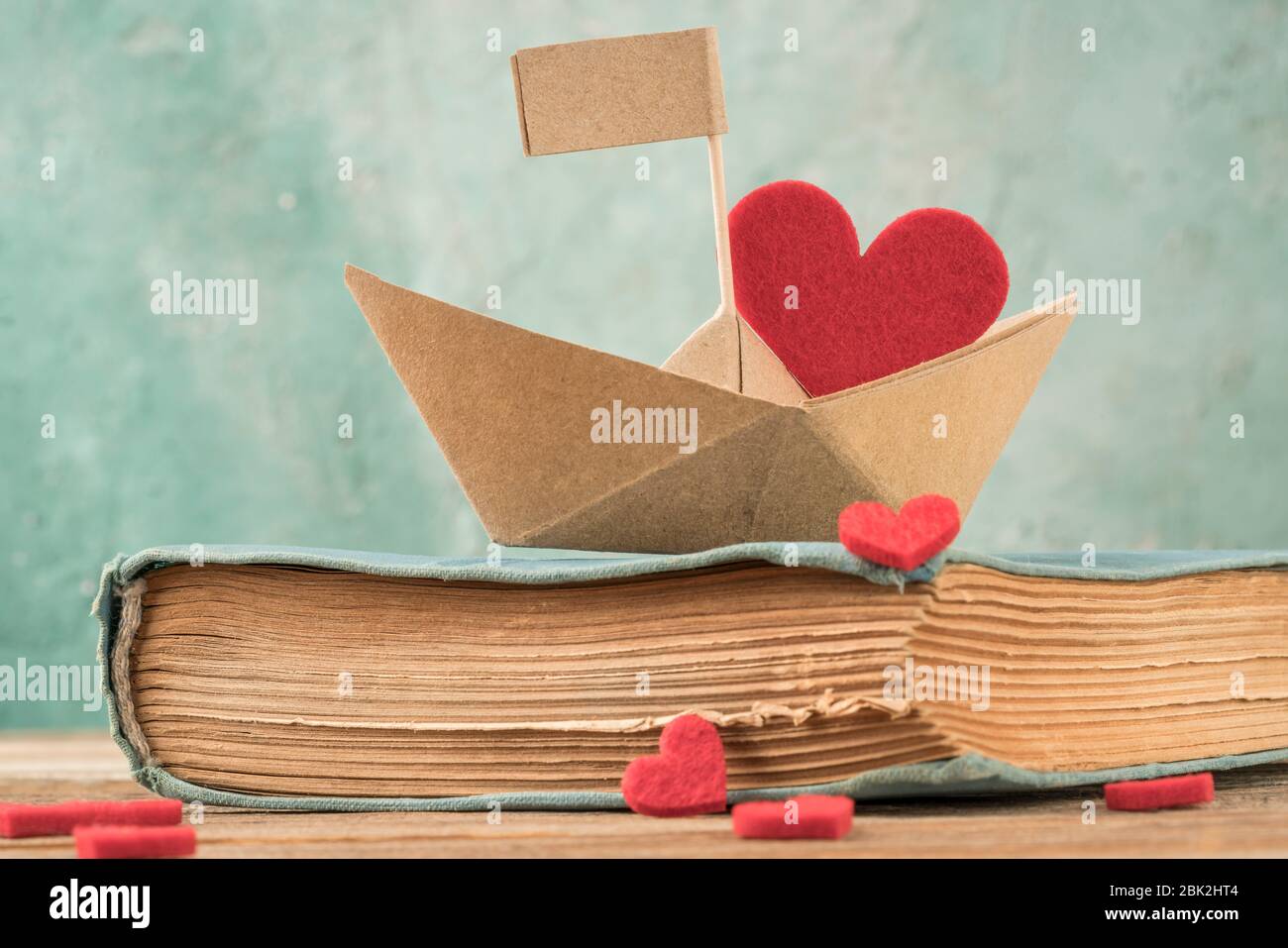 paper boat on an old book on table. Hand crafted origami paper sailing ...