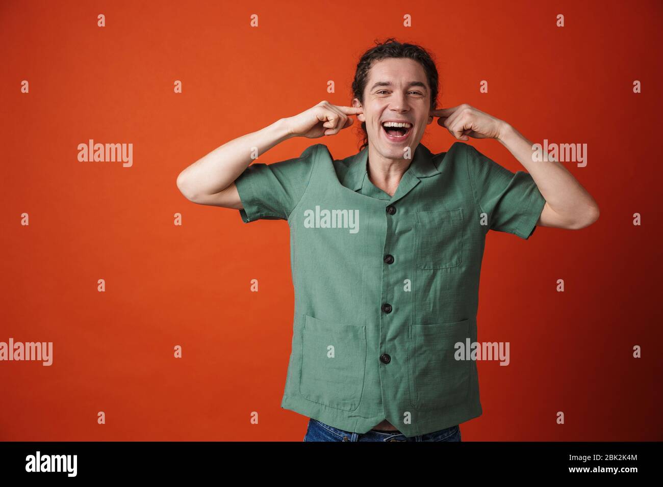Image of happy handsome man laughing and plugging his ears isolated ...