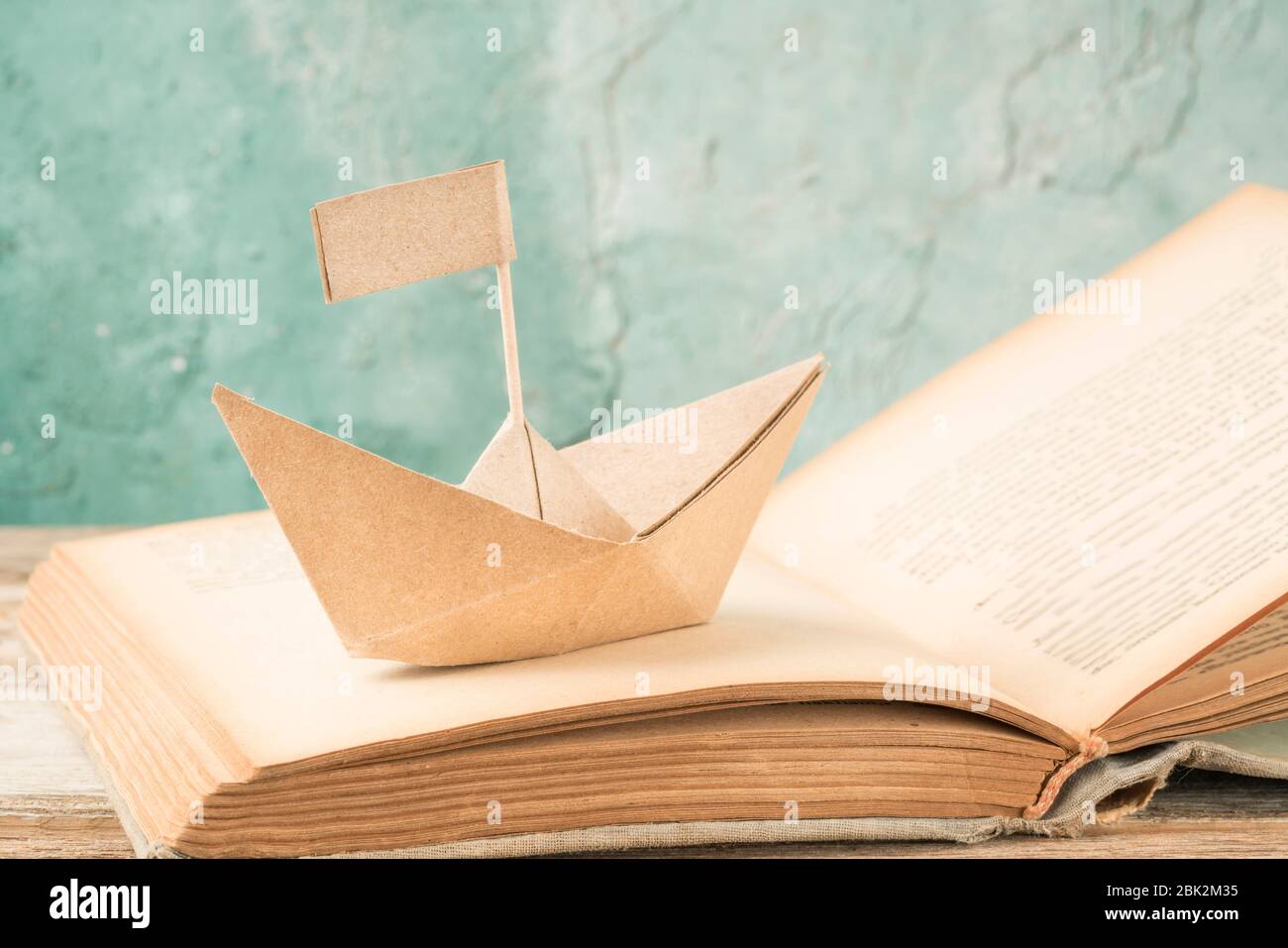 paper boat on an old book on table. Hand crafted origami paper sailing ...
