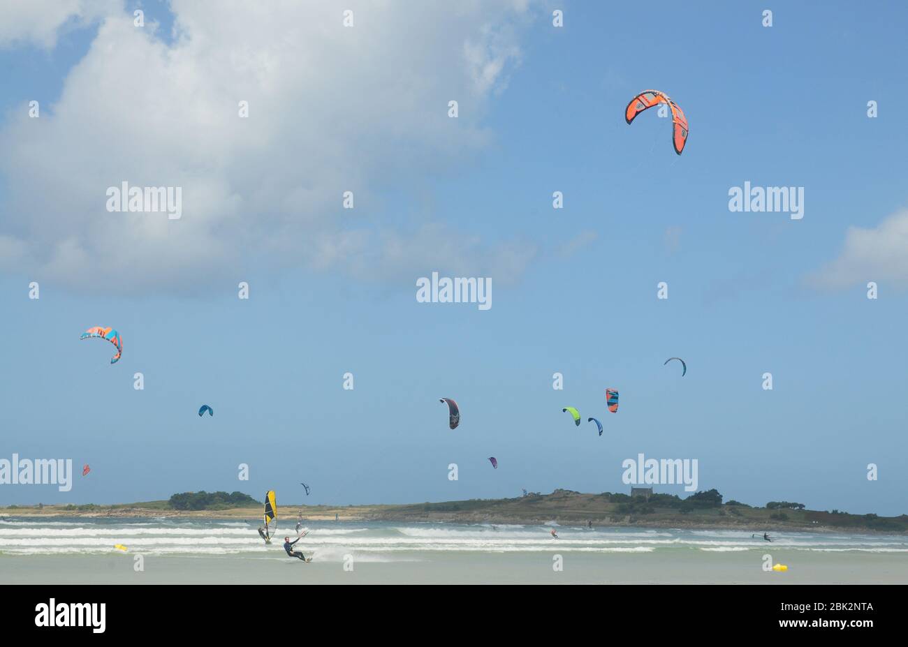 Windsurfers and kite surfers enjoy windy conditions on a beach near ...