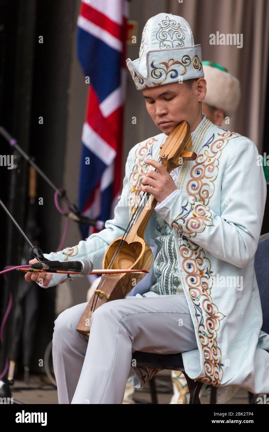 Portrait of a man in traditional clothing playing a kobyz on a stage at ...