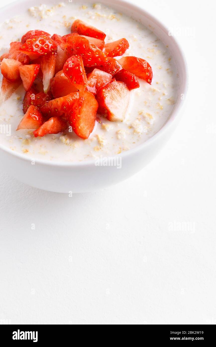 Close up of oats porridge with strawberry in bowl over light stone ...