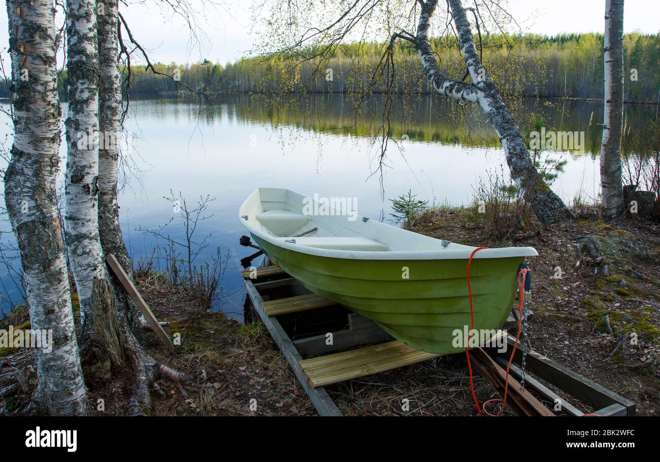Green fiberglass rowboat docked at lake shore , Finland Stock Photo - Alamy