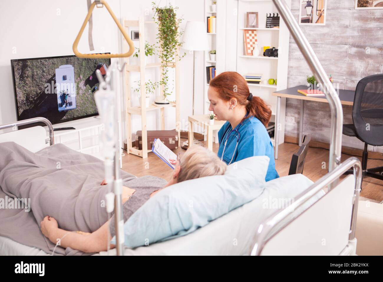 Female doctor in nursing home with senior woman watching tv Stock Photo ...