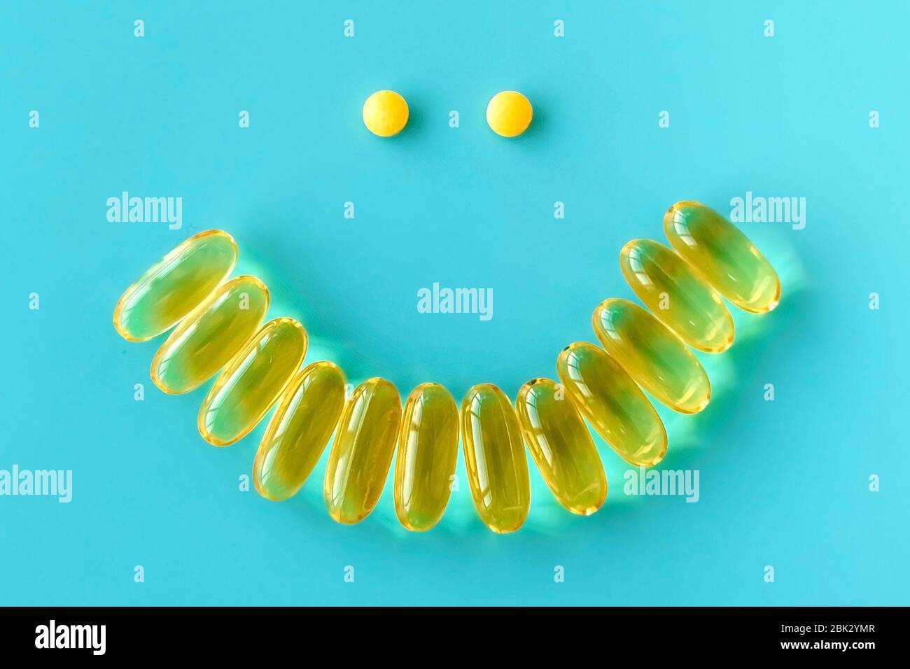 Smile from omega 3 capsules on blue background, positive from pills ...