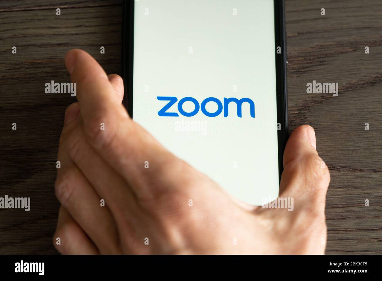Phone with a hand showing Zoom Cloud Meetings app. Work and have ...
