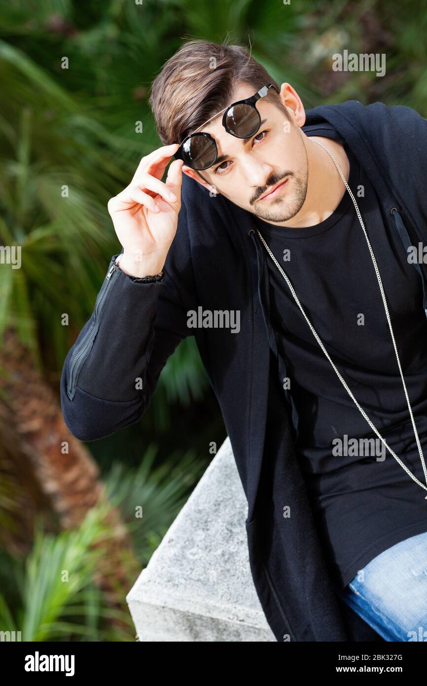 Handsome young man model sitting on the bench. A handsome young man is ...