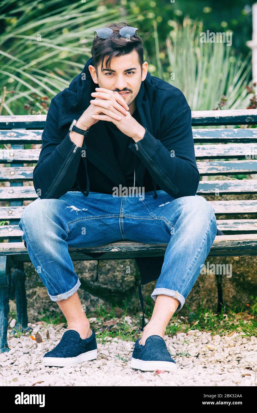 Handsome young man model sitting on the bench. A handsome young man is ...
