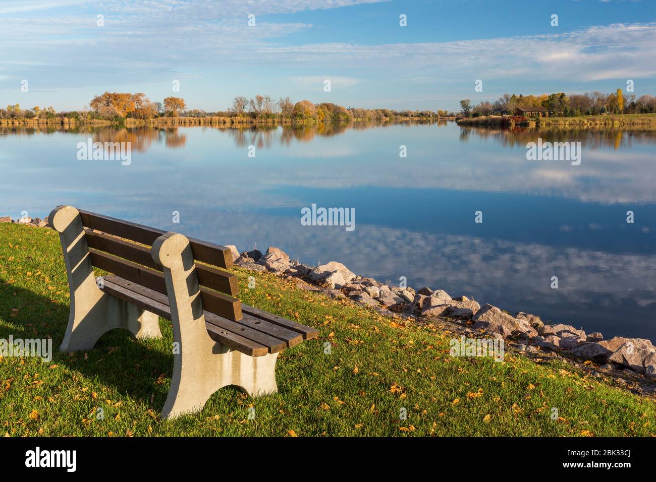 A scenic lake with a park bench during autumn Stock Photo - Alamy