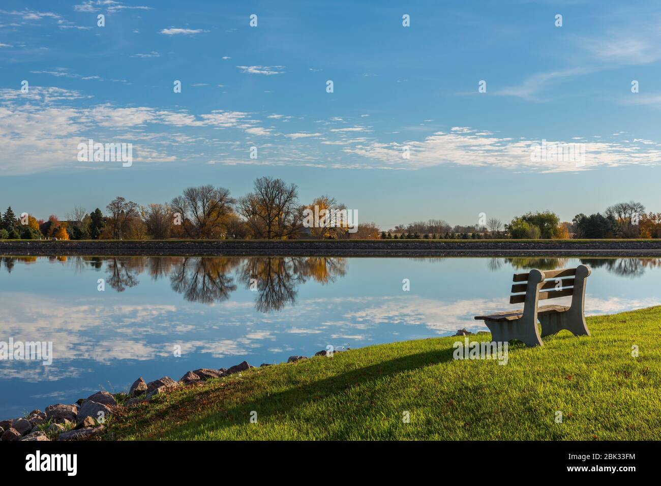 A scenic lake with a park bench during autumn Stock Photo - Alamy