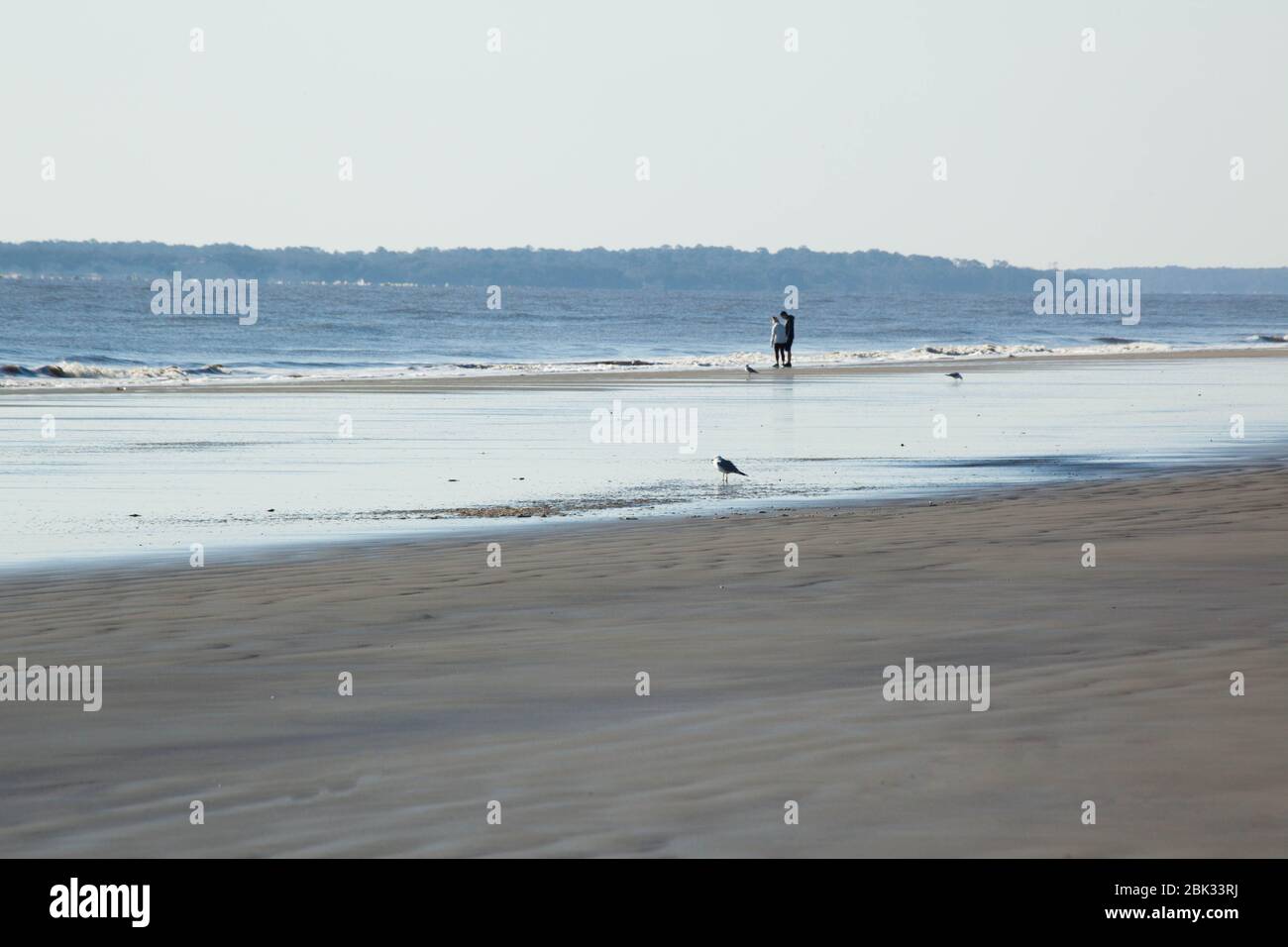Two people on the beach in the distance Stock Photo - Alamy