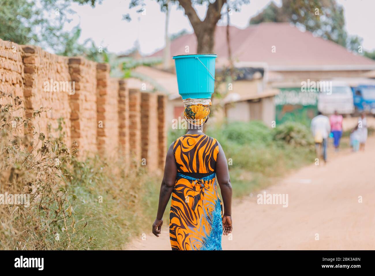 Woman carrying a bucket on her head in Entebbe, Uganda Stock Photo - Alamy