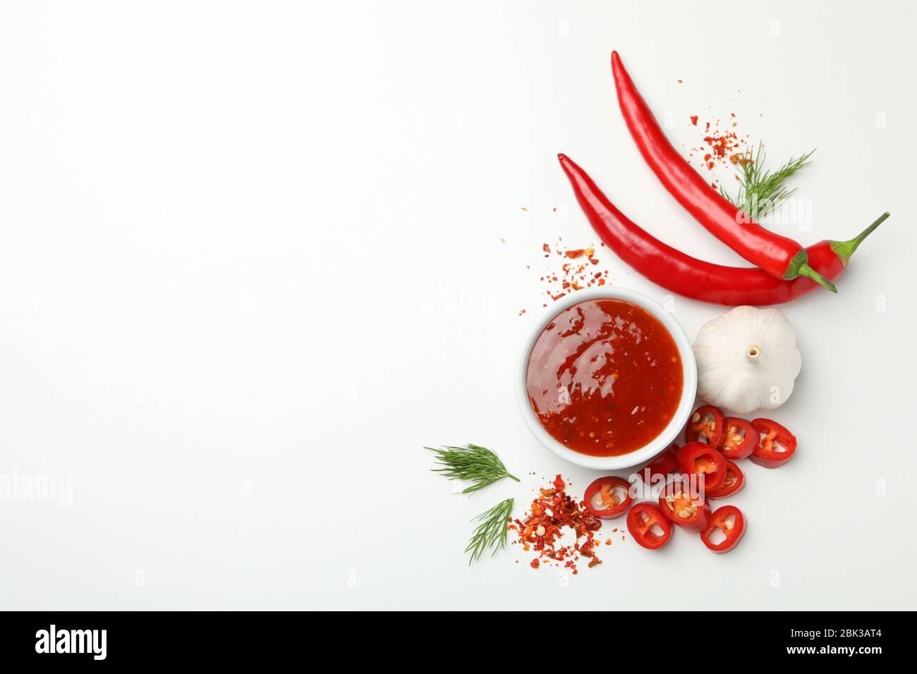Bowl with chilli sauce, pepper and garlic on white background Stock ...