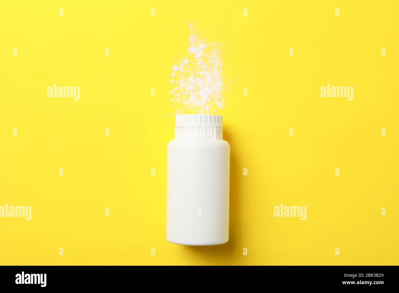 Blank bottle of talcum powder on yellow background, space for text ...