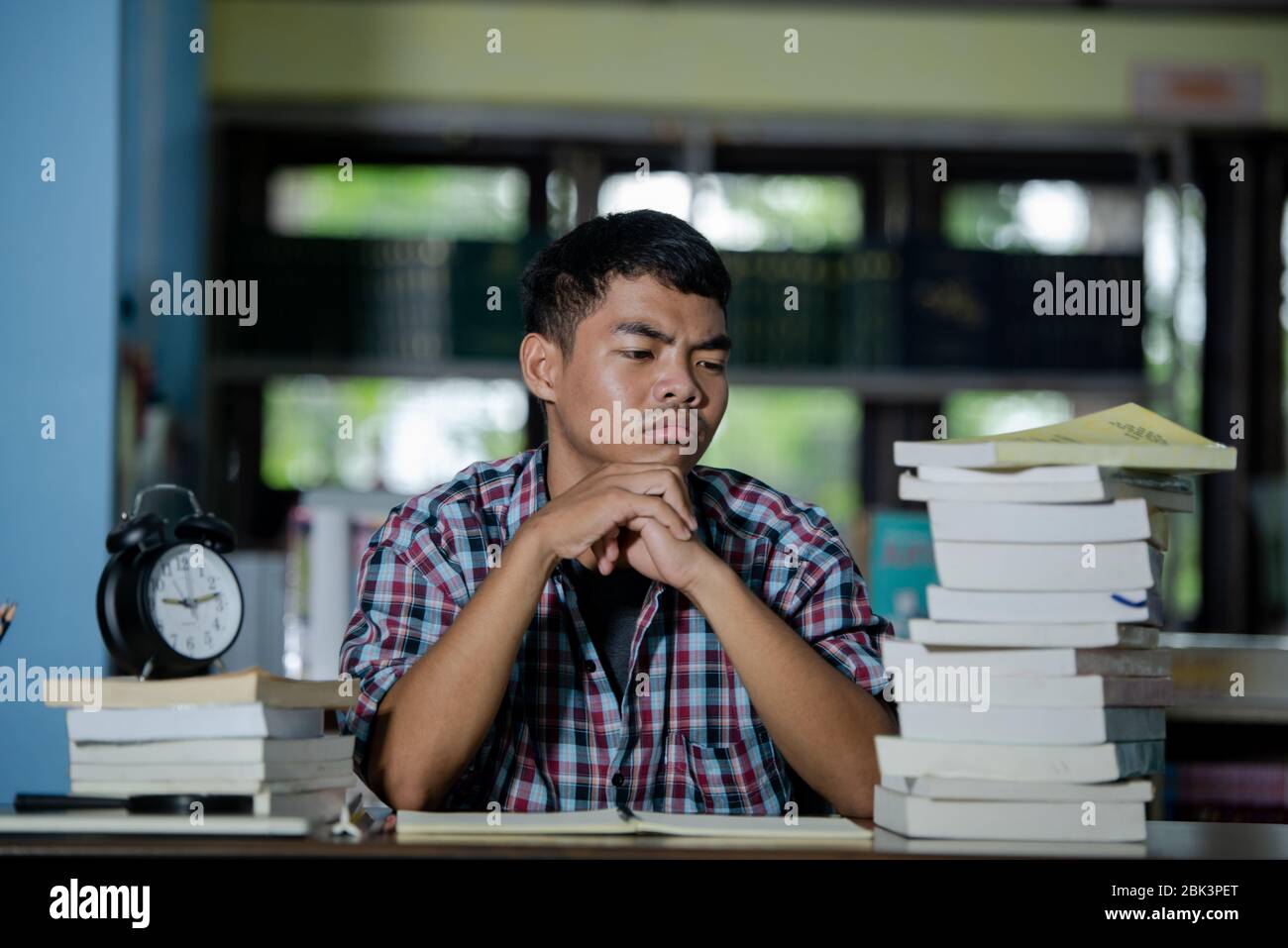 Educational conept: tired student in a library Stock Photo - Alamy