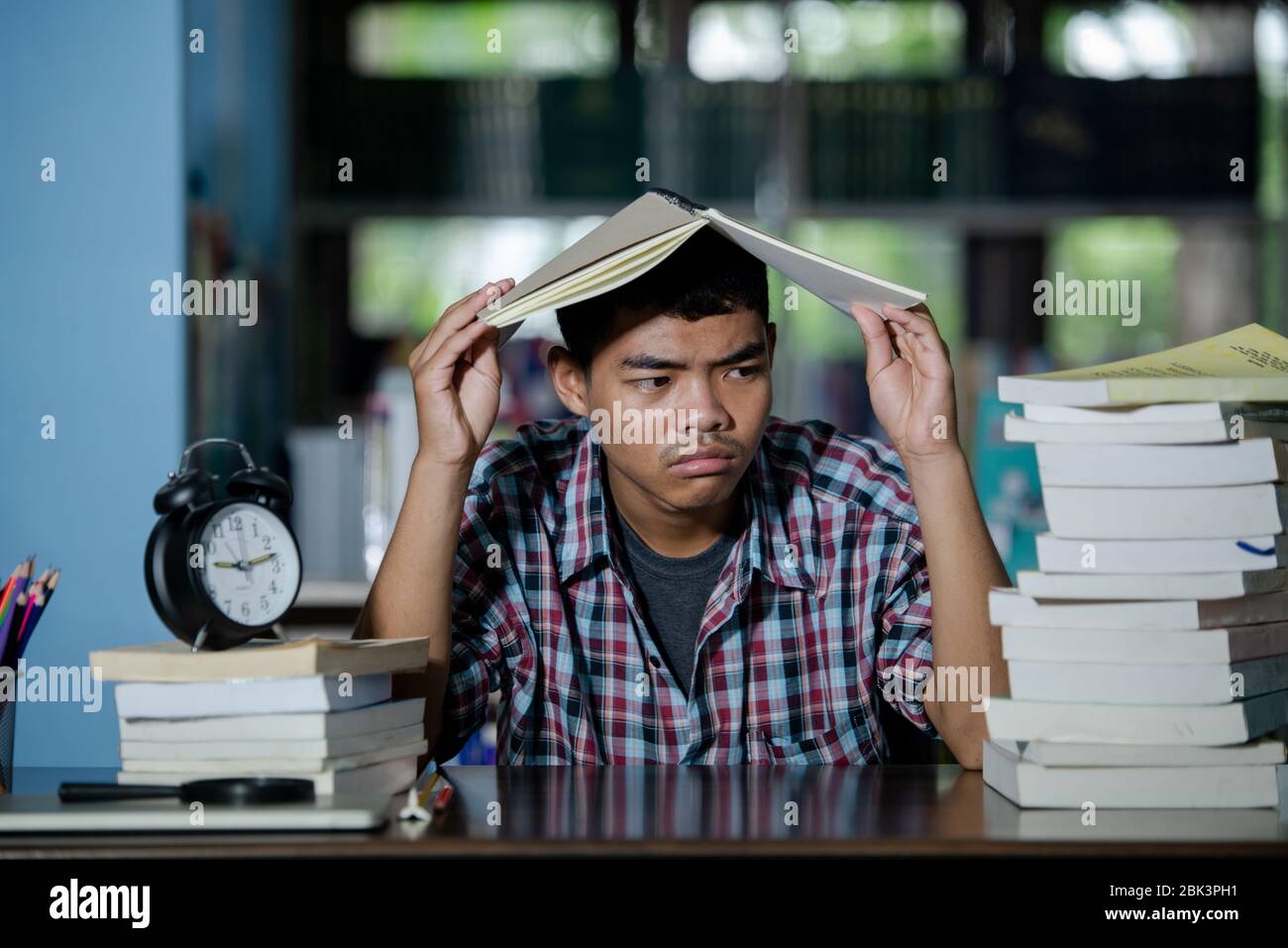 Educational conept: tired student in a library Stock Photo - Alamy