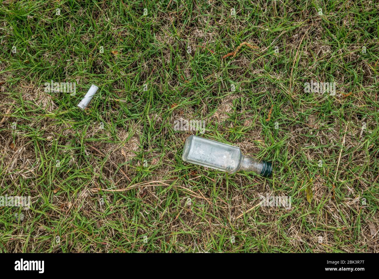 Garbage mini glass liquor bottle and a used cigarette thrown and ...