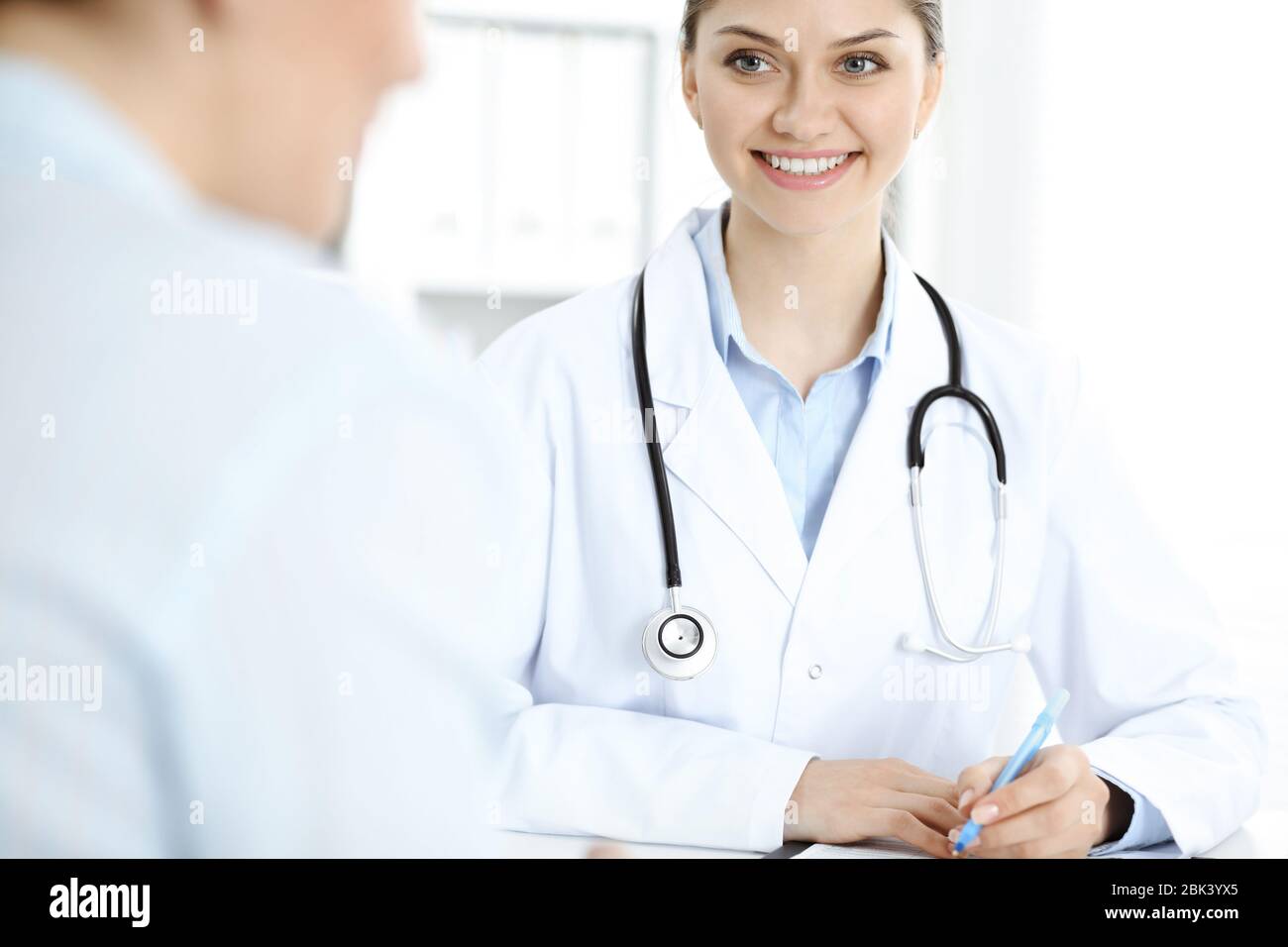 Friendly smiling doctor and patient sitting at the table Stock Photo ...