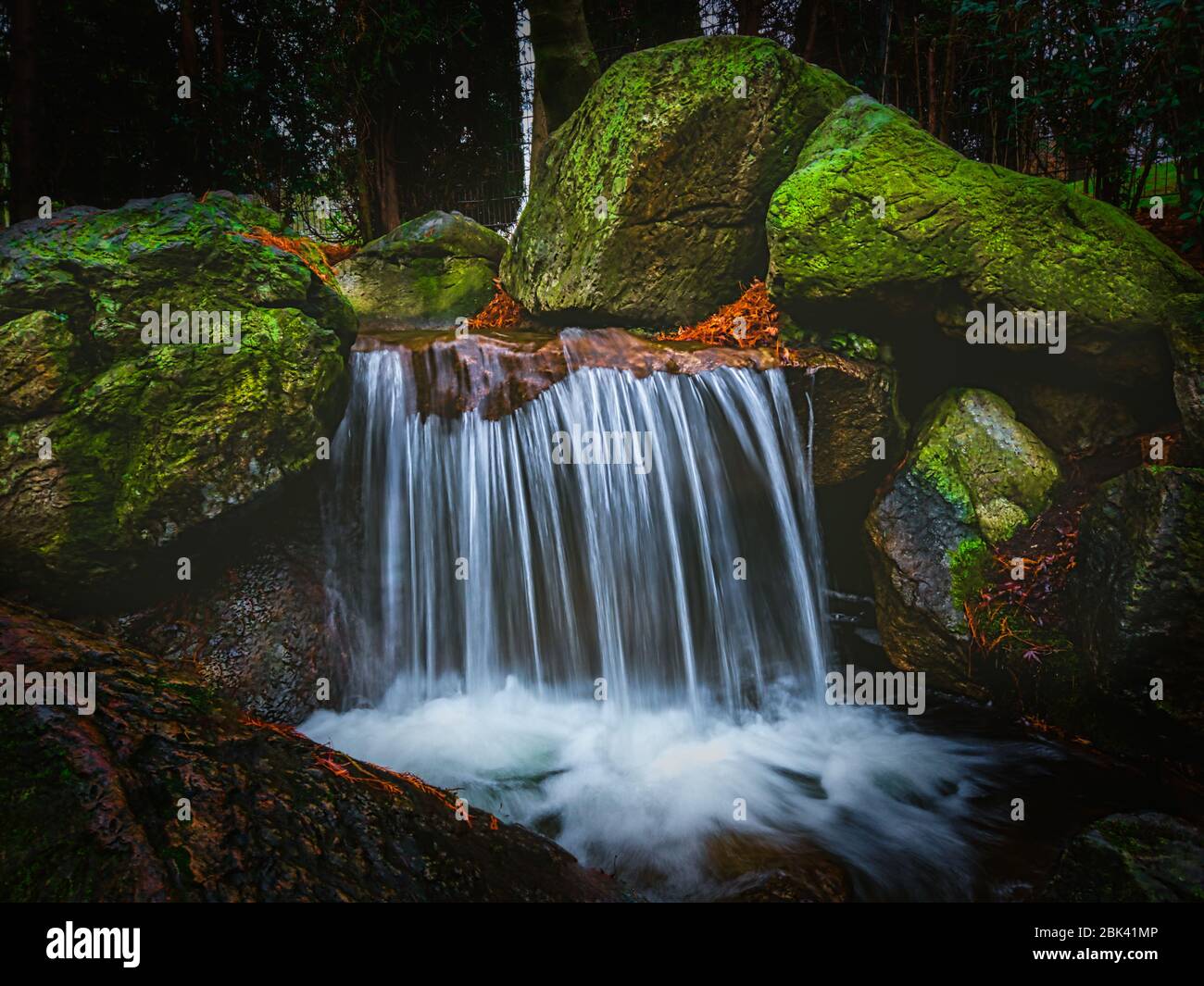 Nice waterfall with blurry water surrounded by the mossy boulders ...