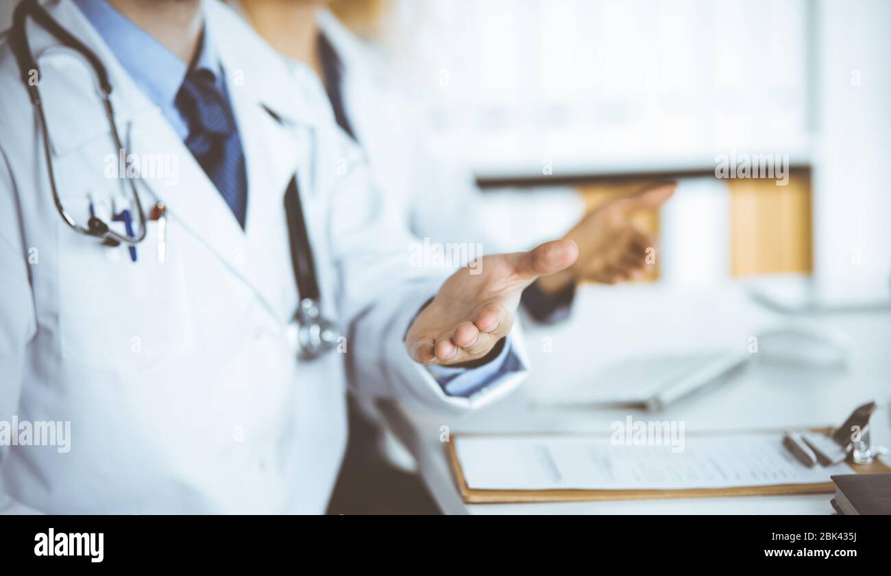 Two doctors sitting and offering helping hand for shaking hand or ...