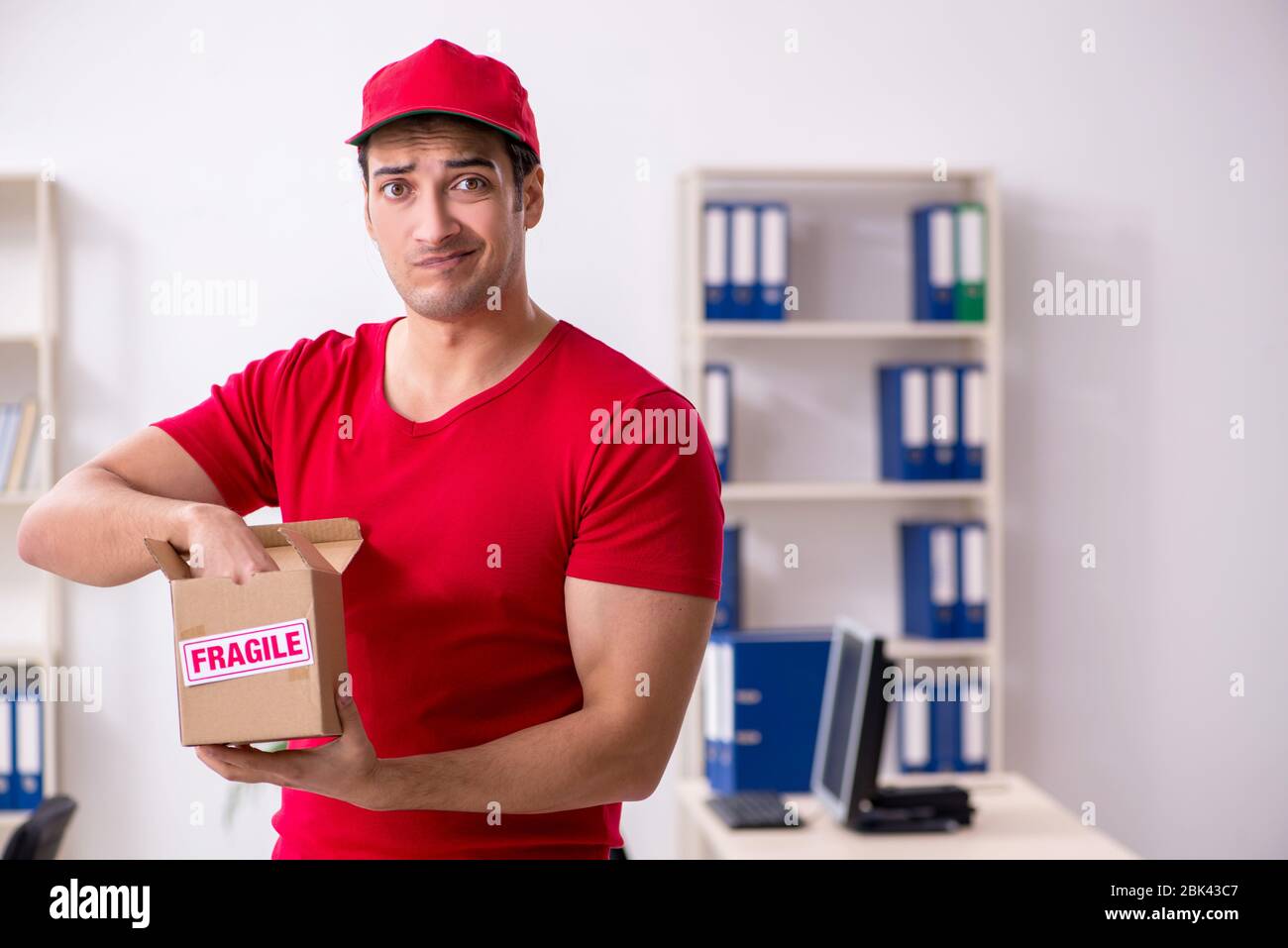 Young courier delivering postbox to the office Stock Photo - Alamy