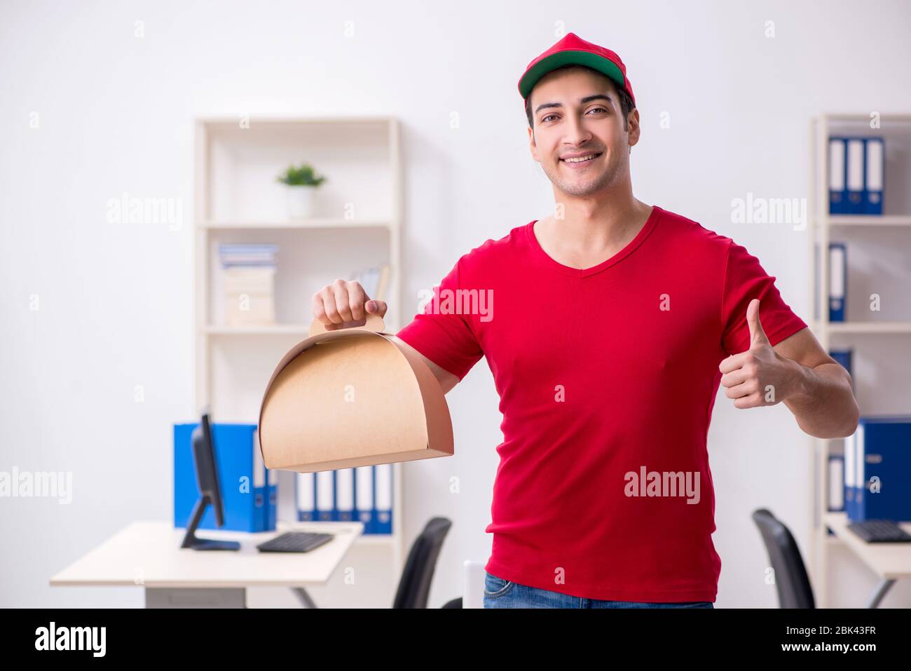 Young courier delivering cake to the office Stock Photo - Alamy