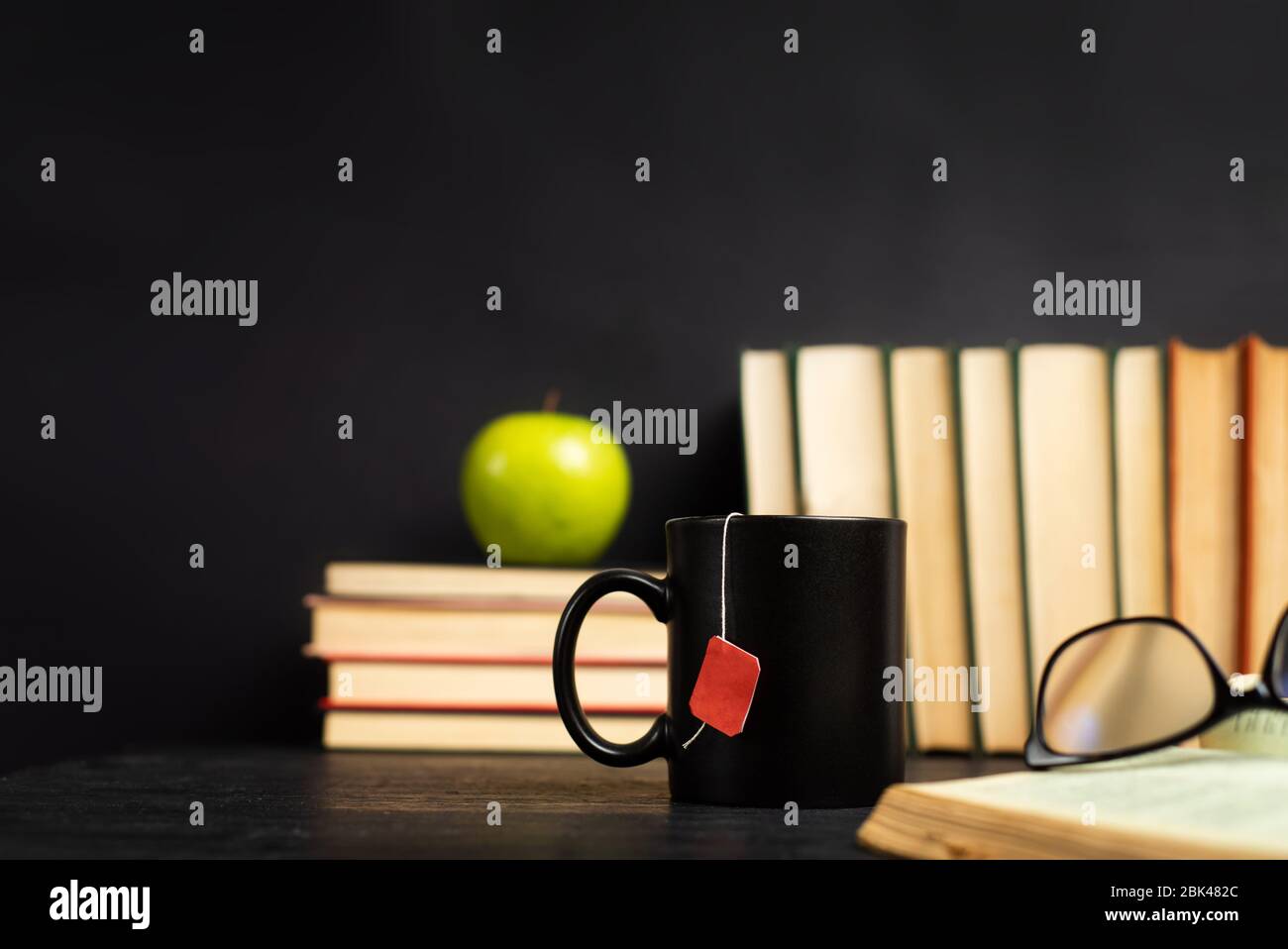 Pile of books with cup of tea for reading on a dark table with copy ...