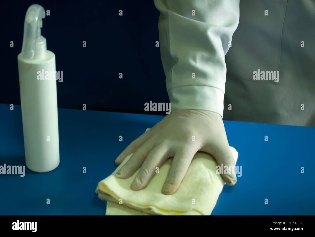 You can see the blue table, spray bottle, the hand treating the surface ...