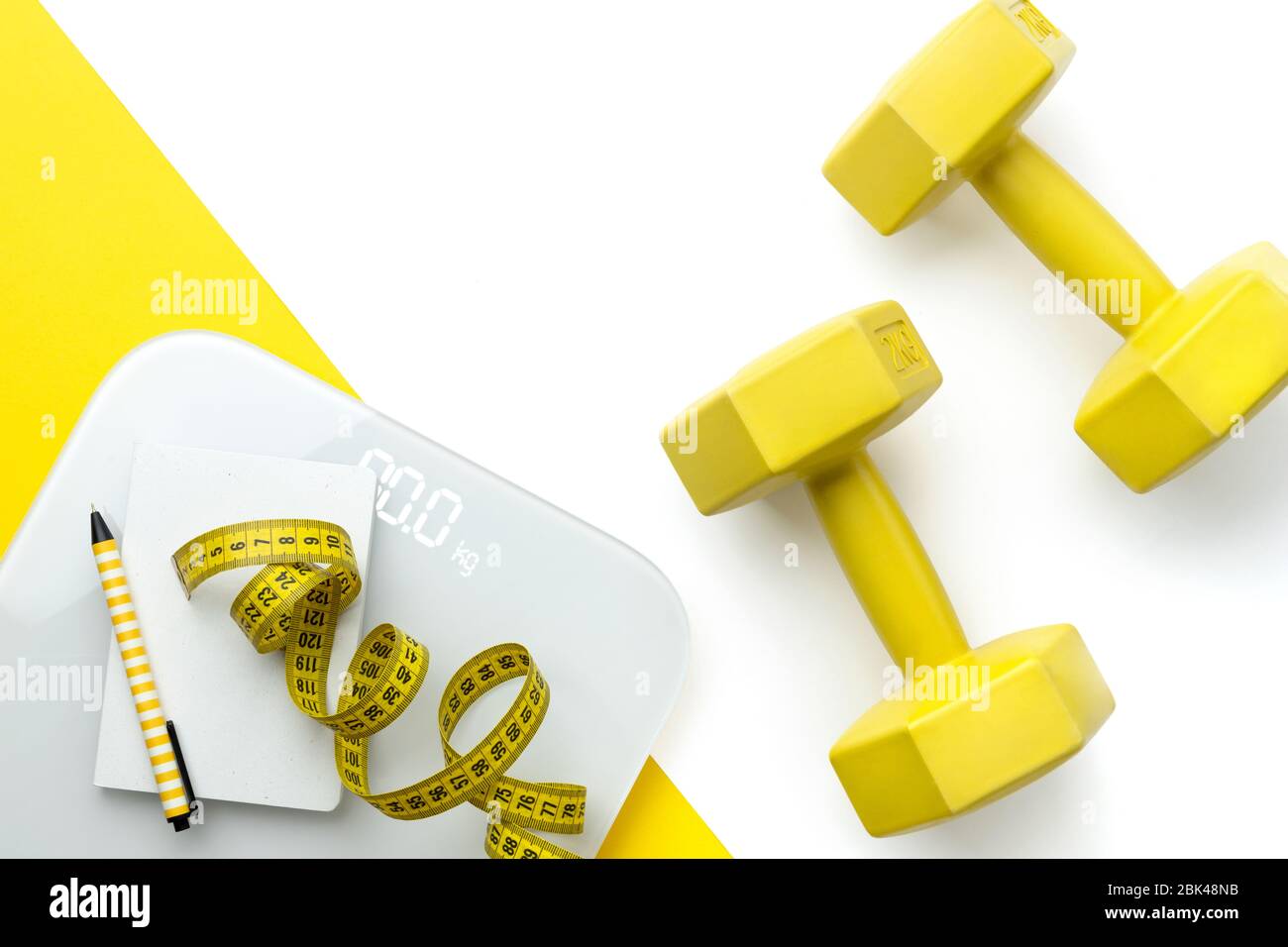 Flat lay top view scales, dumbbell and tape measure on white yellow ...