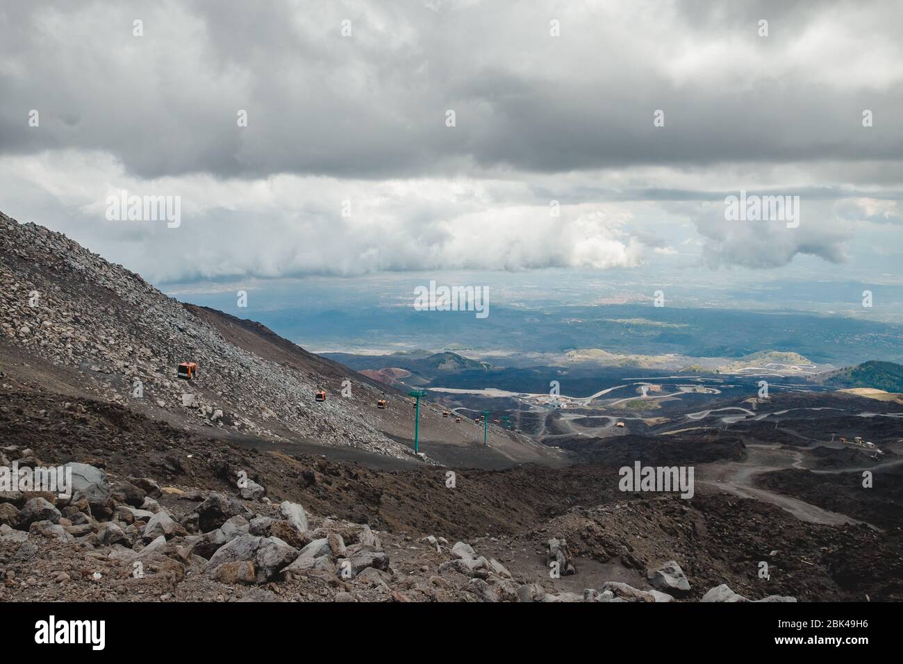 Top of crater Mount Etna volcano, frozen cold lava smokes, thick clouds ...