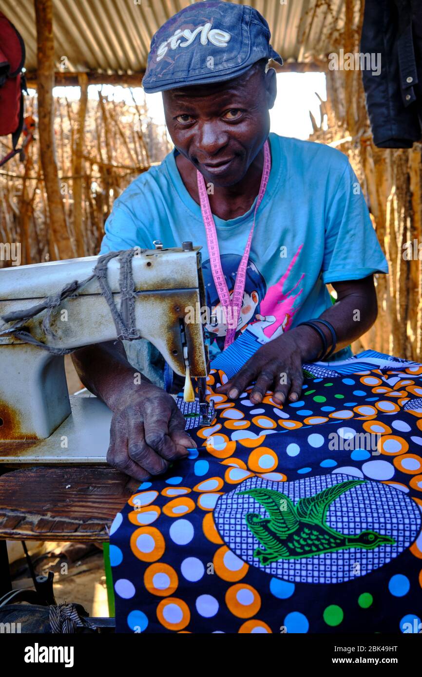 Street tailor sewing a piece of colorful cloth with an old sewing ...