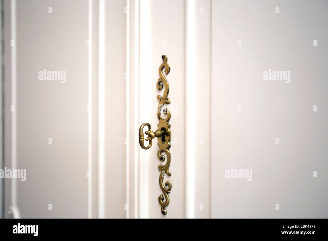 White cupboard doors with Golden key in keyhole, luxury antique design ...