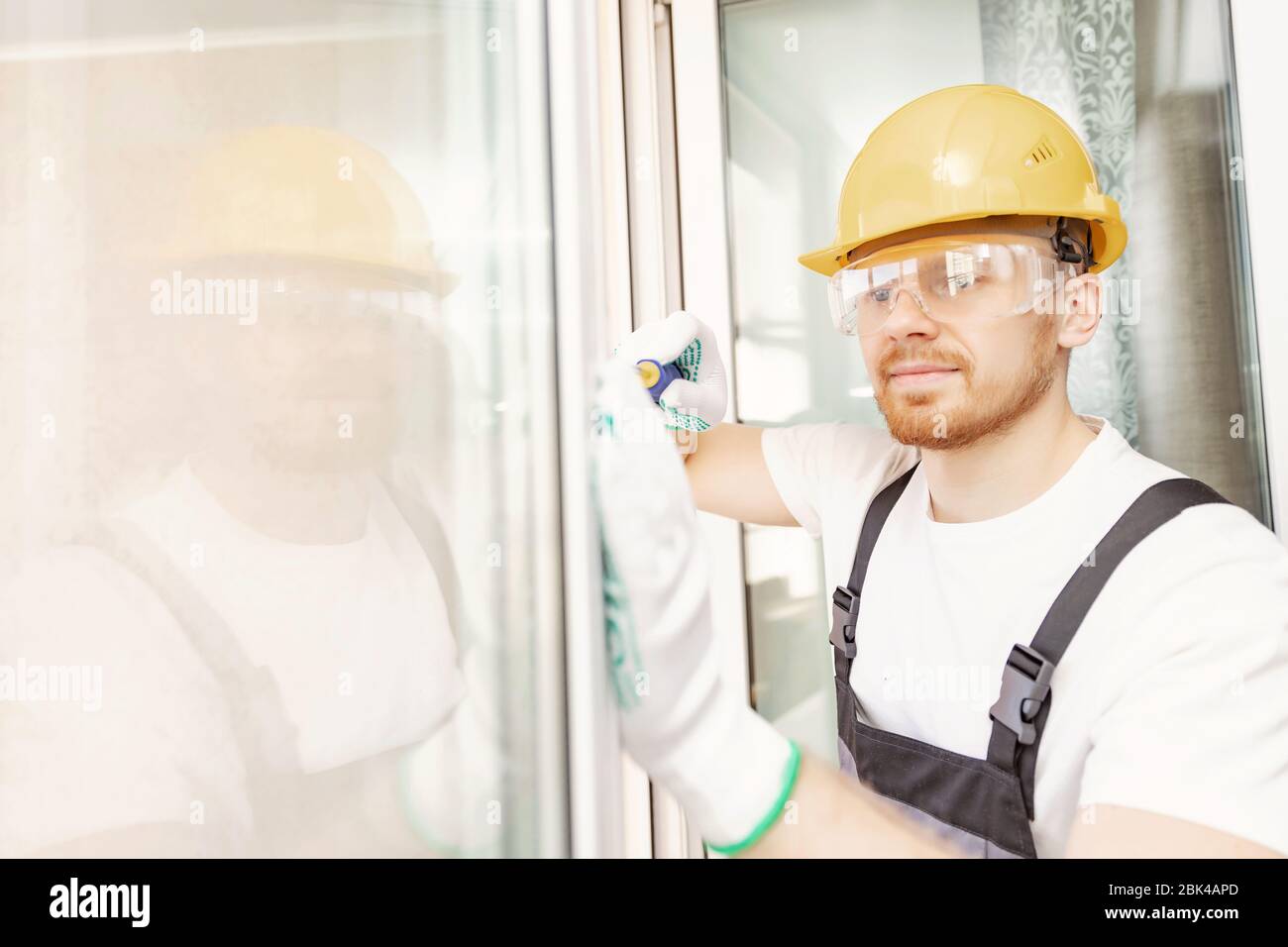 Worker man installs plastic windows and doors with double-glazed white ...