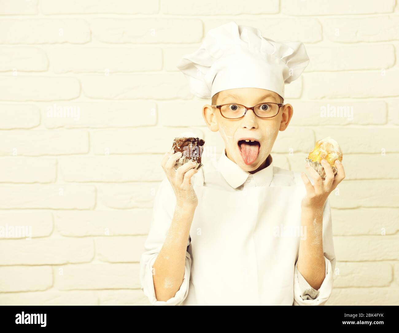 young boy cute cook chef in white uniform and hat on stained face flour ...