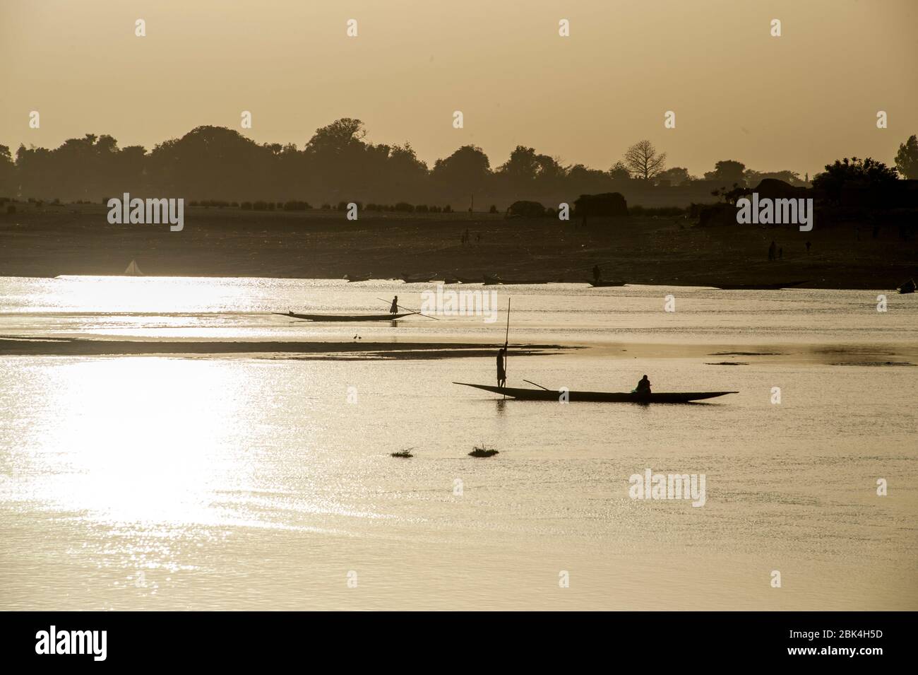 Local people in wooden canoes at sunset on the Bani River in Mopti in ...